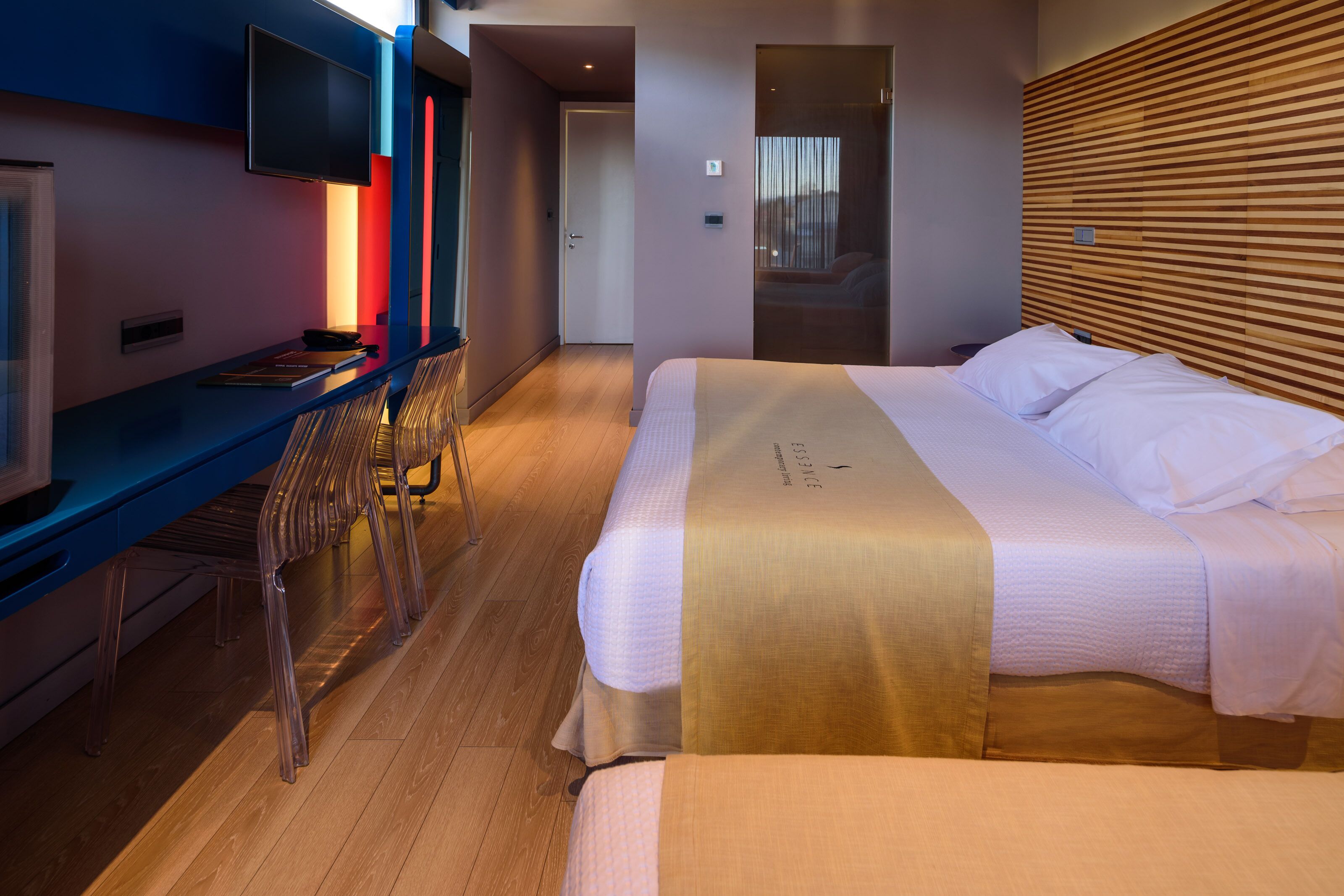 Quarto de hotel com cama, escrivaninha e cadeira.