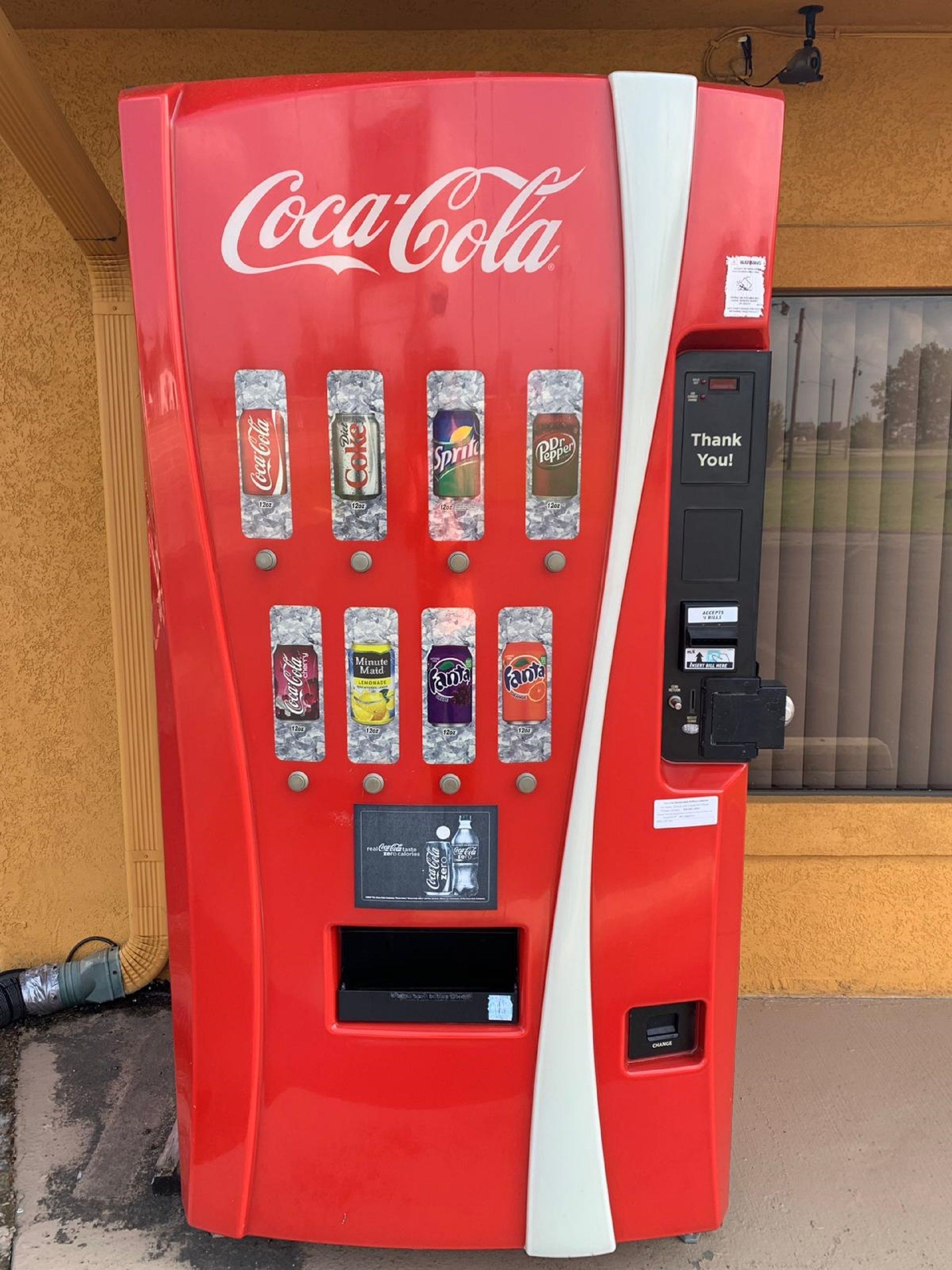 Máquina automática de Coca-Cola com diversas opções de bebidas e interface de pagamento.