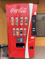 Máquina automática de Coca-Cola com diversas opções de bebidas e interface de pagamento.