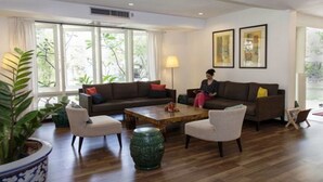 Uma sala de estar moderna com um conjunto de sofás, uma mesa de centro e uma grande janela que proporciona iluminação natural.
