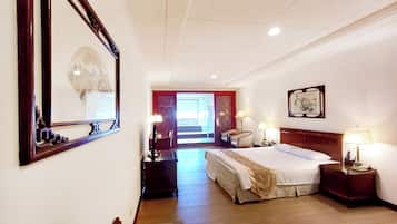 Quarto de hotel com cama grande, luminárias de cabeceira, escrivaninha e espelho.