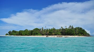 Uma ilha tropical com águas turquesa cristalinas, uma praia arenosa e vegetação verde exuberante.