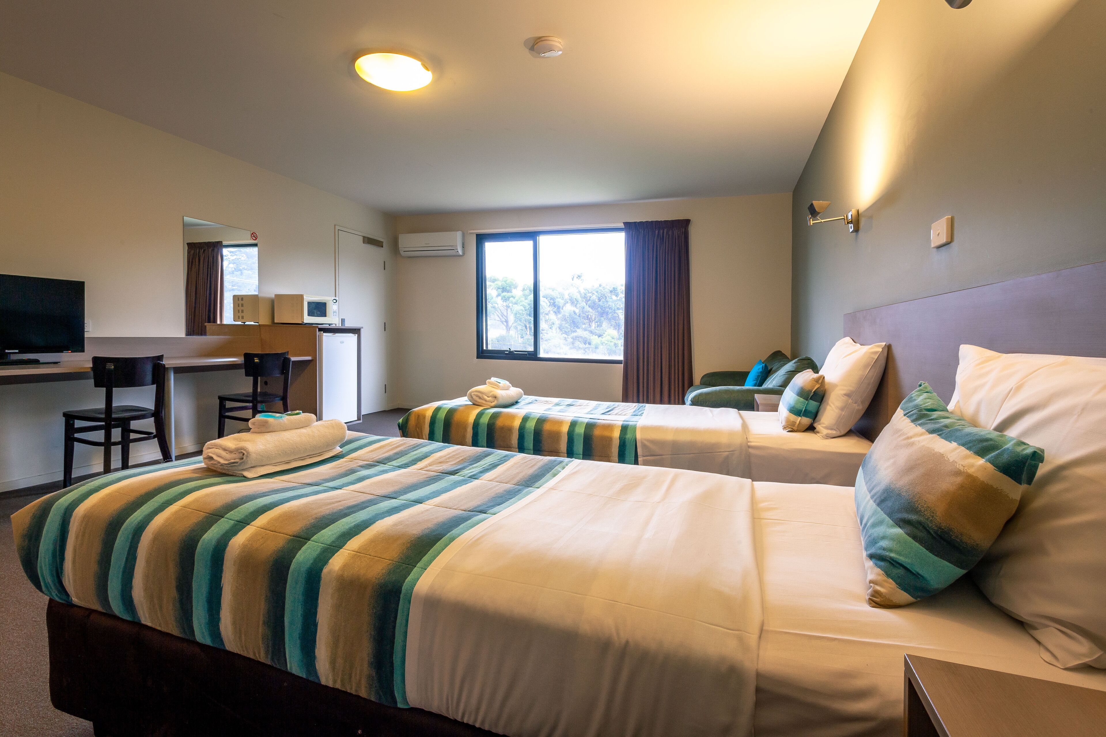 Quarto de hotel com duas camas, uma mesa e uma televisão.