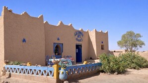 Um edifício com estilo arquitetônico marcante, uma porta azul e uma placa com a inscrição 'Les Aunes'.