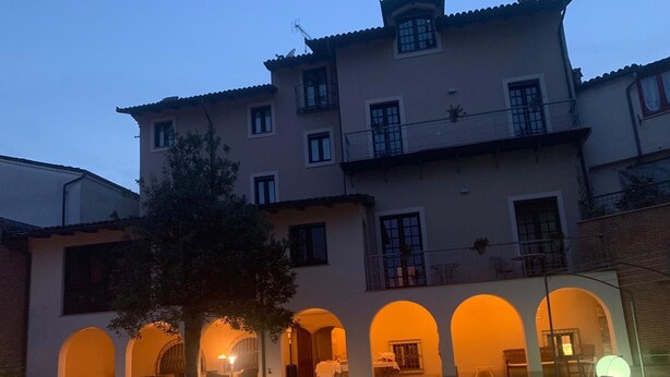 Um edifício de vários andares com um pátio, com varandas em arco e áreas de estar ao ar livre.