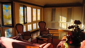 Um quarto com duas poltronas, um sofá, uma mesa de centro e um vaso de flores.