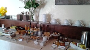 Buffet de café da manhã com diversos alimentos, incluindo pães, doces e acompanhamentos.