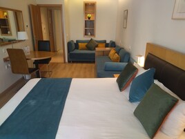 Quarto de hotel com cama, sofá, escrivaninha e cadeira.