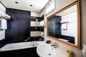 Uma casa de banho moderna com banheira, pia e um espelho grande.