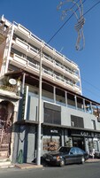 Um hotel de vários andares com design moderno, com varandas e um letreiro grande com a palavra 'HOTEL'.