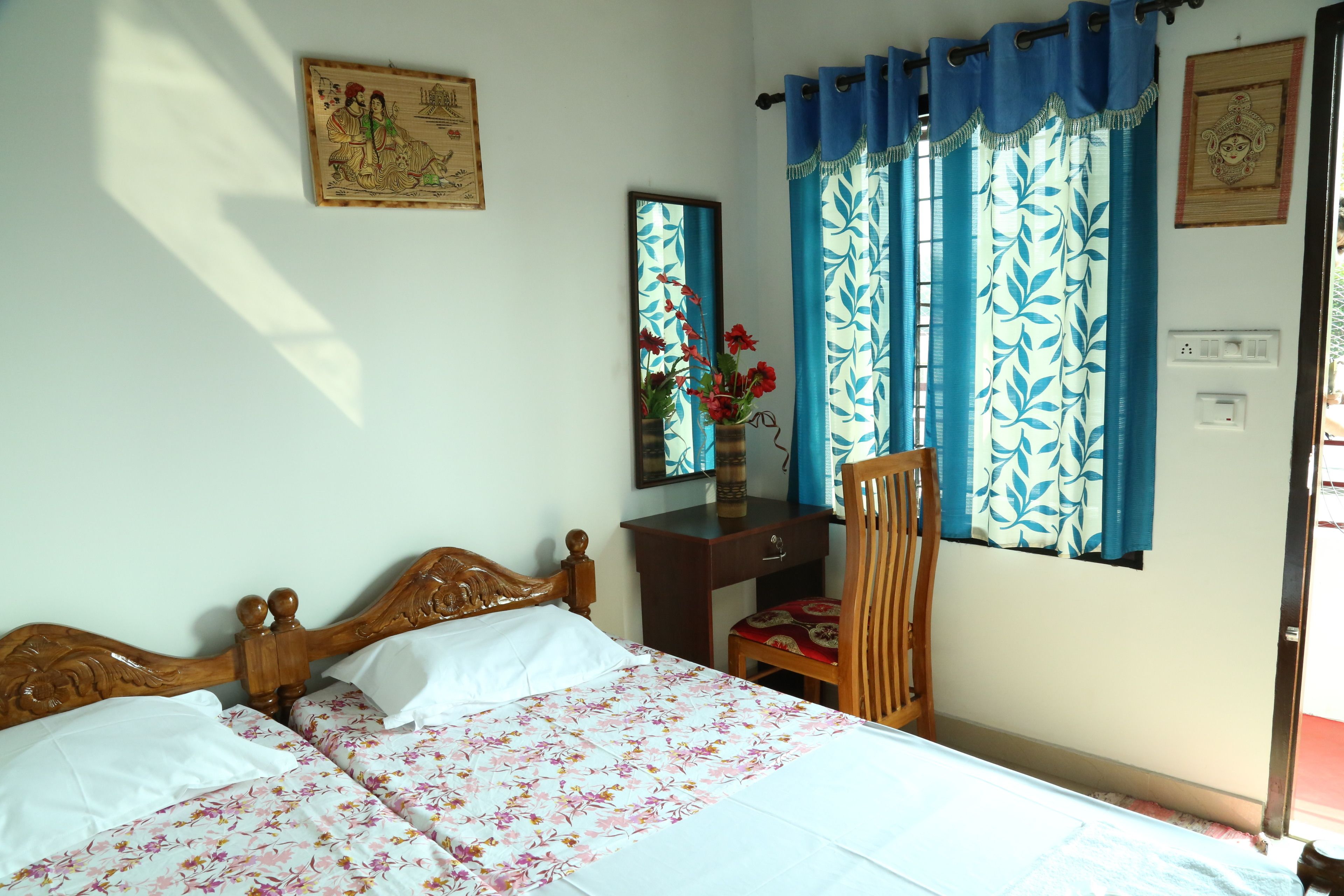 Quarto com cama de madeira, escrivaninha, cadeira e janela com cortinas azuis.