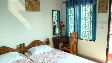 Quarto com cama de madeira, escrivaninha, cadeira e janela com cortinas azuis.