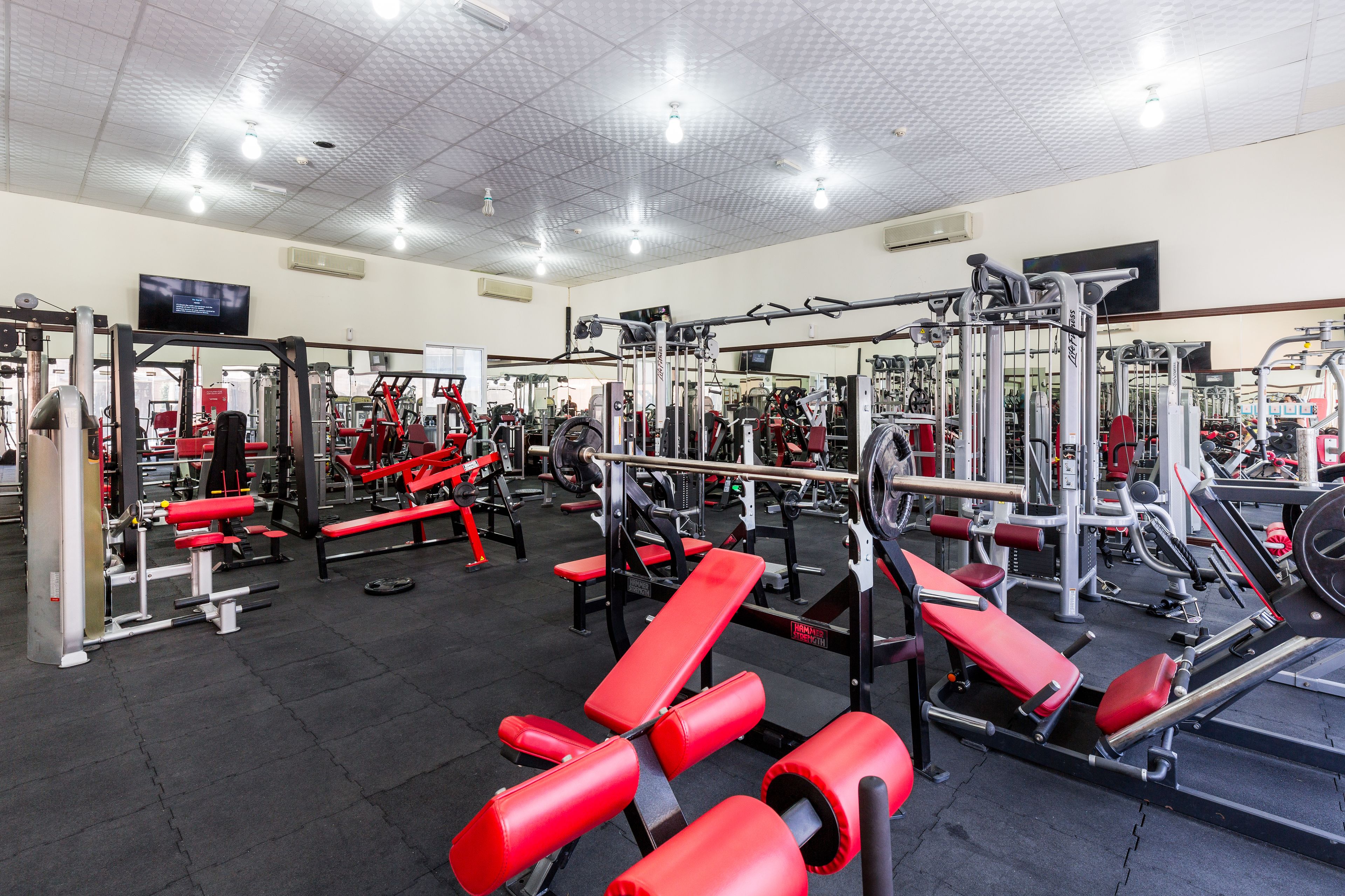Uma academia com diversos equipamentos de exercícios, incluindo bancos e máquinas de musculação.