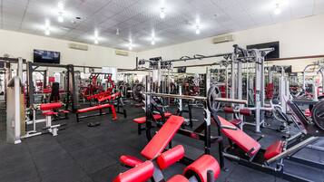 Uma academia com diversos equipamentos de exercícios, incluindo bancos e máquinas de musculação.