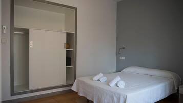Um quarto com cama, guarda-roupa e mesa de cabeceira.