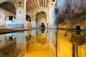 Interior com tetos abobadados, piso espelhado e paredes de pedra.