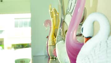 Uma bancada de cozinha com objetos decorativos, incluindo uma peça em formato de cisne, um vaso rosa e branco, e um conjunto de colheres amarelo e rosa.