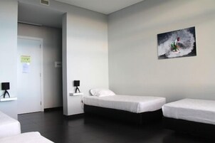 Quarto de hotel com duas camas de solteiro, um quadro na parede e uma porta que dá para outro cômodo.