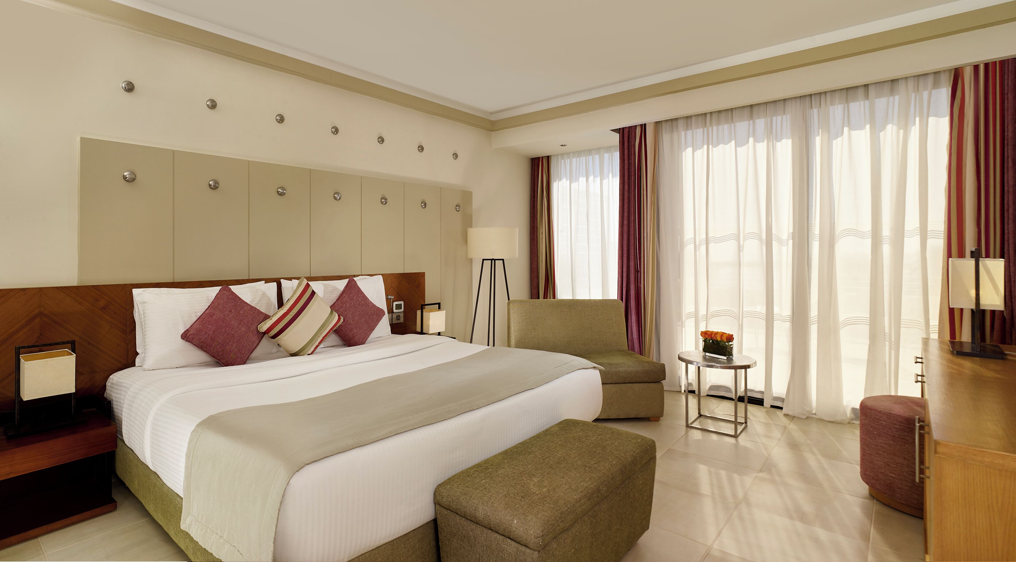 Quarto de hotel com uma cama grande, um sofá, uma pequena mesa e uma escrivaninha.