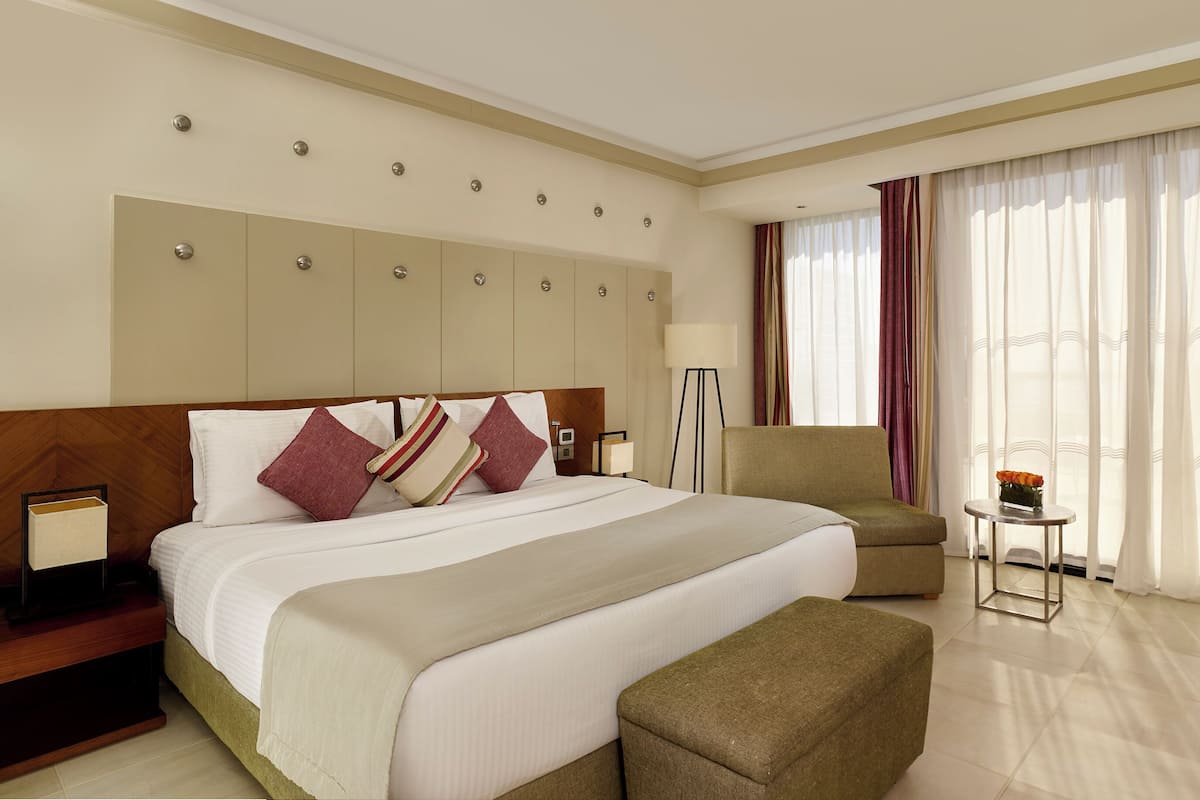 Quarto de hotel com uma cama grande, um sofá, uma pequena mesa e uma escrivaninha.