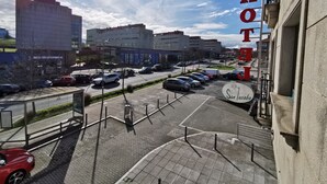 Hotel com vista para a rua e carros estacionados.