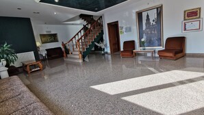 Um hall espaçoso com piso de granito polido, escada de madeira e uma grande moldura na parede.