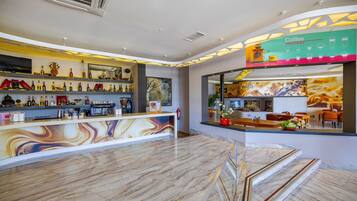 Uma área de bar moderna com piso de mármore, um canto de café e diversas garrafas e copos em prateleiras.