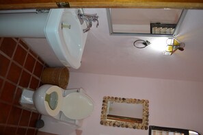 Casa de banho com sanita, lavatório e espelho.