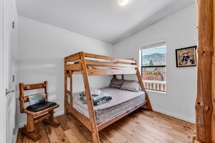 Quarto com beliche, um banco de madeira e janela com vista para o exterior.