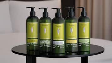 Cinco produtos de higiene pessoal Verveine sobre uma mesa preta em quarto de hotel.