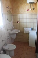 Casa de banho com sanita, bidé, lavatório e espelho.