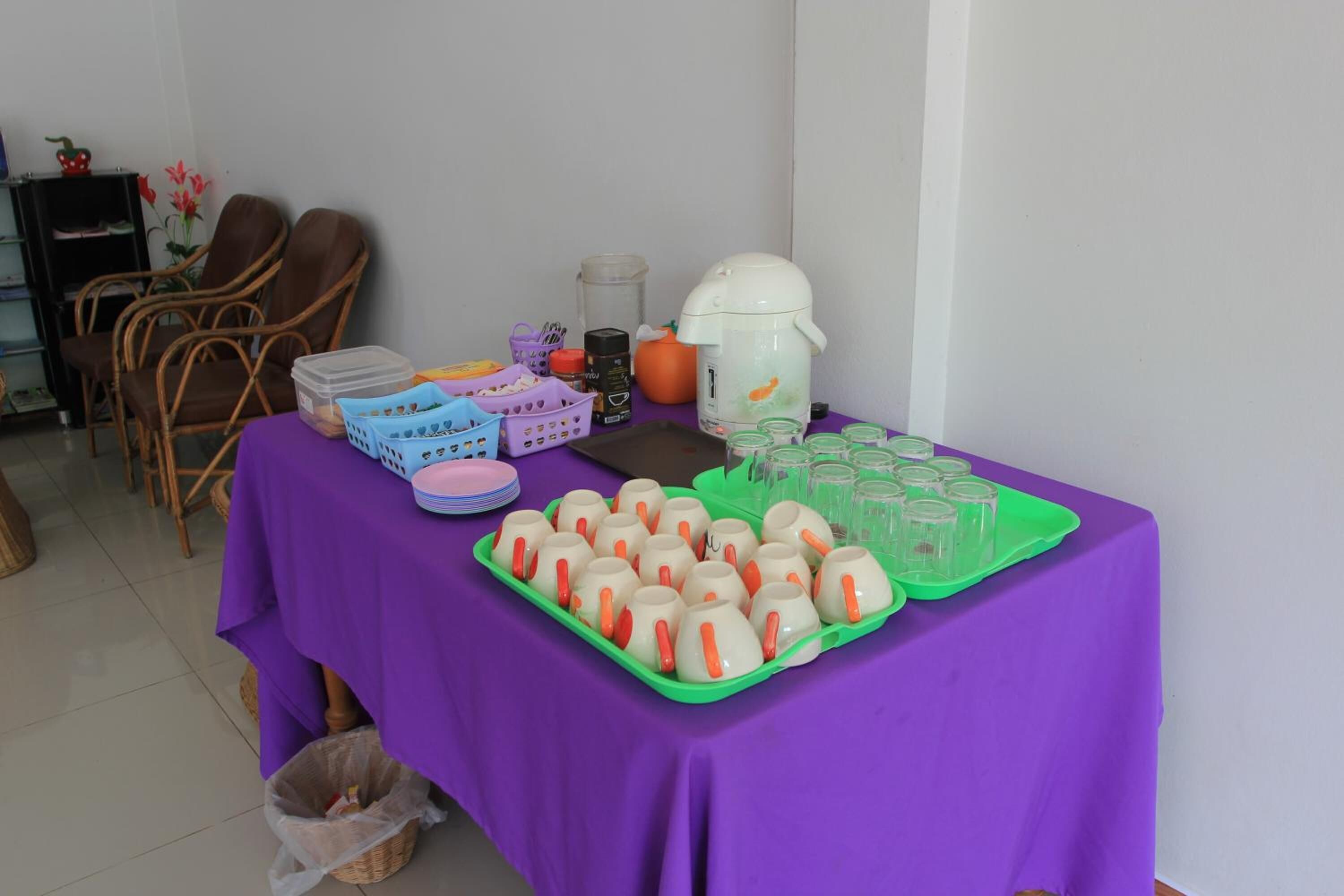 Mesa com toalha roxa, diversos recipientes e utensílios de cozinha.