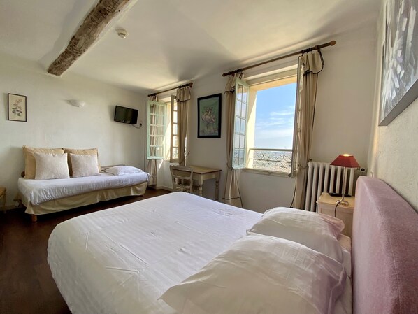 Quarto com uma cama grande, uma escrivaninha, uma cadeira e um radiador.