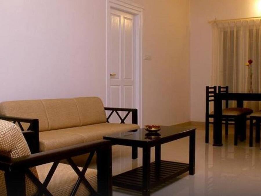 Uma sala de estar com um sofá, uma mesa de centro e uma mesa de jantar com cadeiras.