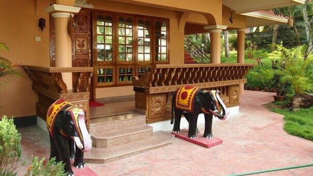 Um edifício com varanda, duas estátuas de elefante e uma escadaria que leva à entrada.