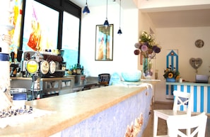 Uma área de bar com balcão, torneiras de cerveja e um espaço de estar com mesa e cadeiras.