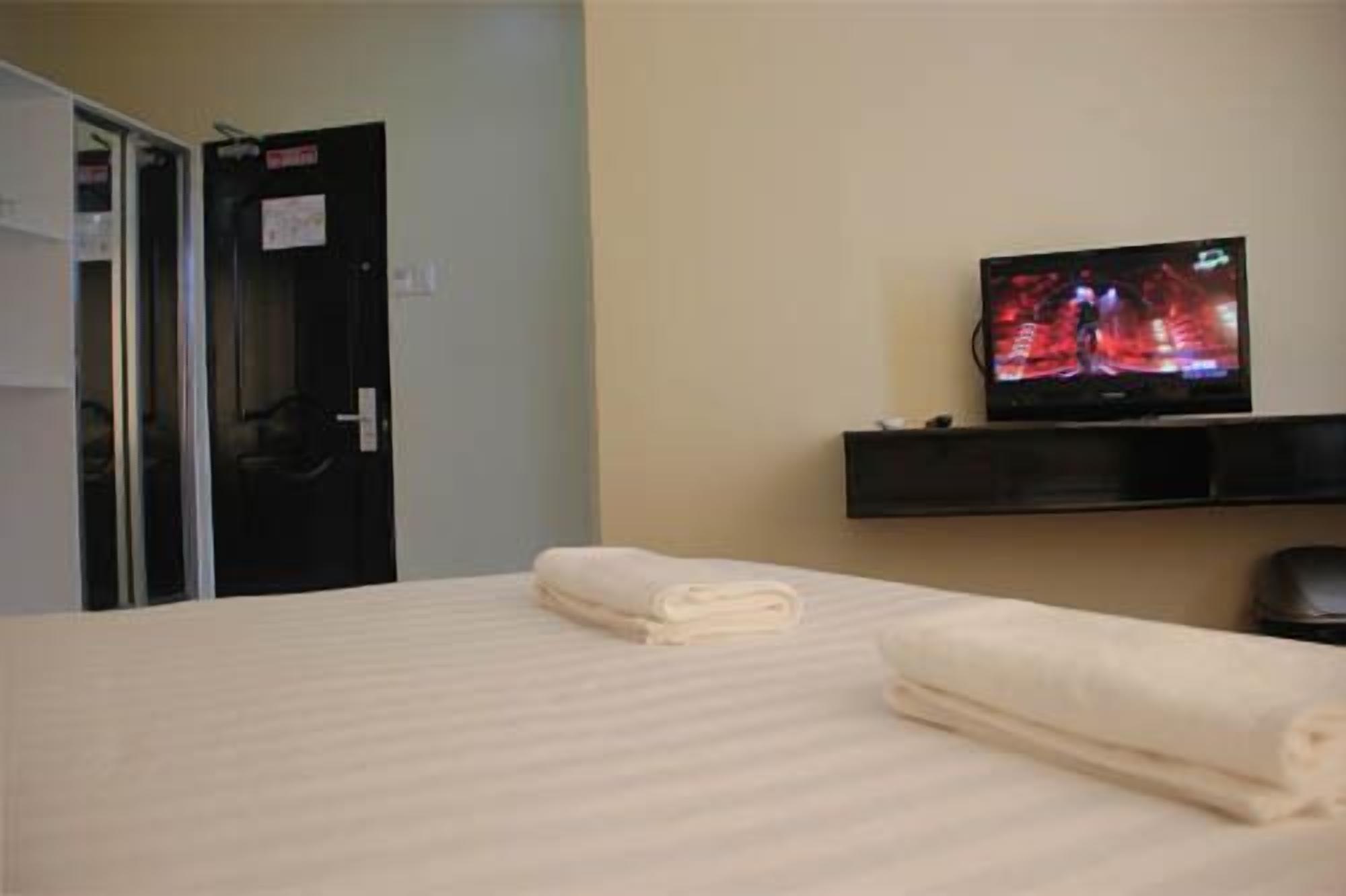 Quarto de hotel com uma cama, televisão na parede e uma porta.