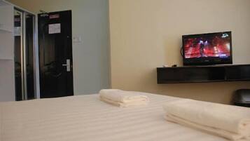 Quarto de hotel com uma cama, televisão na parede e uma porta.