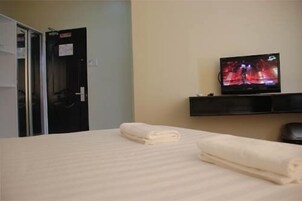Quarto de hotel com uma cama, televisão na parede e uma porta.