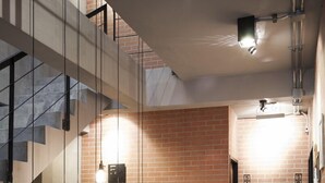 Interior moderno com escada, paredes de tijolos aparentes e luminárias pendentes.