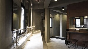 Casa de banho moderna com balcão comprido, várias pias e zona de bar com banquetas.