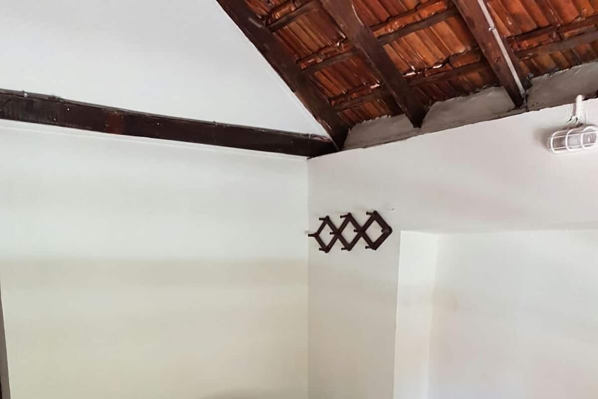 Quarto pequeno com cama de solteiro, estrutura de madeira e colchão branco.
