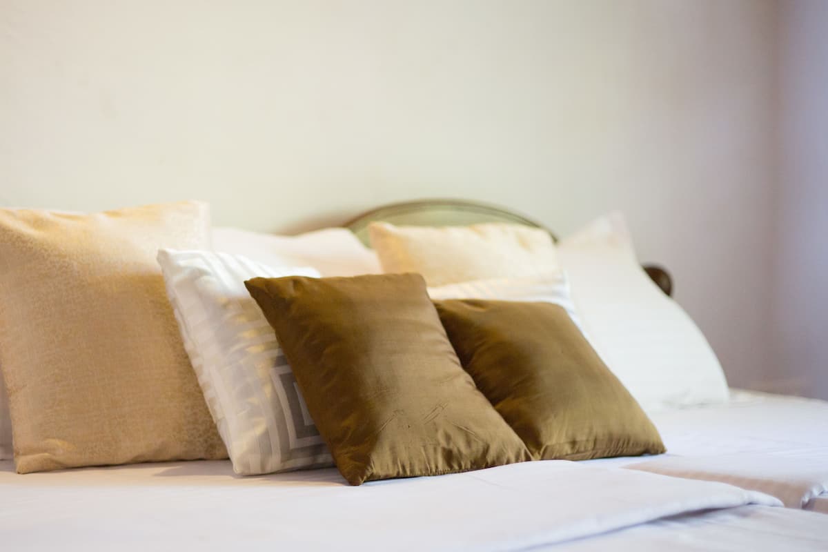 Cama com vários travesseiros em cores diferentes.