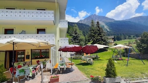 Hotel com área externa para sentar, vista para as montanhas e parquinho.