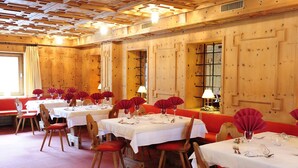 Restaurante com várias mesas preparadas para refeições, paredes de painel de madeira e um ambiente interno acolhedor.