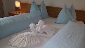 Quarto de hotel com uma cama, roupa de cama azul claro, cabeceira de madeira e almofadas decorativas.