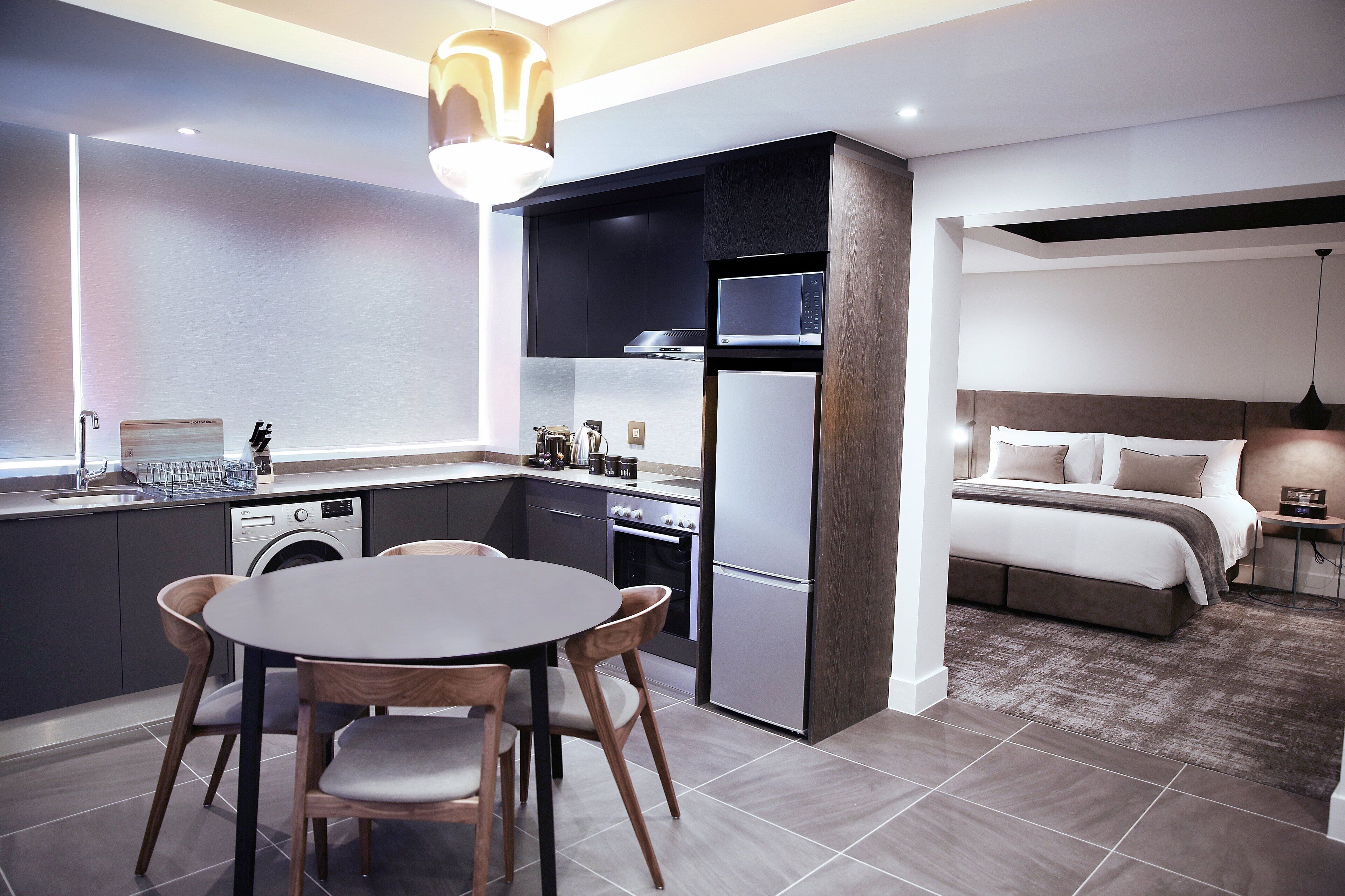Quarto de hotel compacto com cozinha compacta, área de refeições e cama.