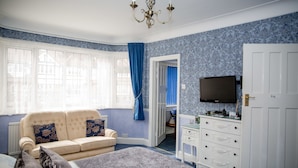 Quarto com cama grande, sofá, televisão e guarda-roupa.