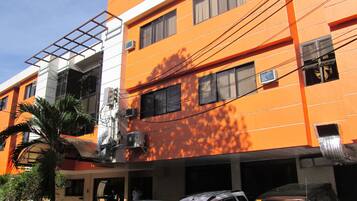 Um edifício de vários andares com fachada laranja vibrante, unidades de ar condicionado e uma garagem subterrânea.