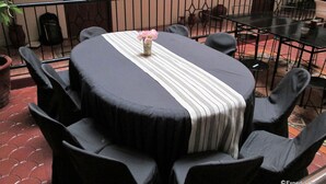 Mesa redonda com toalha de mesa preta e um corredor de mesa listrado, cercada por cadeiras pretas.